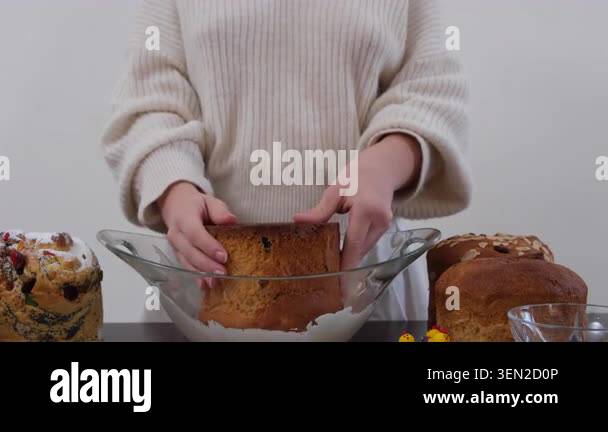 A woman carefully turns a freshly baked Easter bread upside down and ...