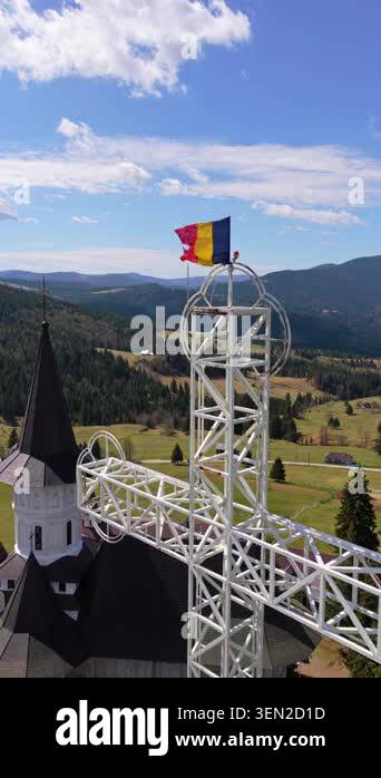 Aerial drone view of a Romanian flag waving above the large metal cross ...