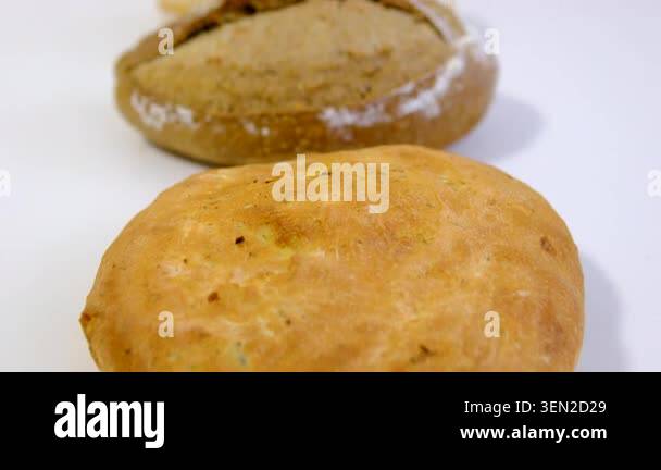 Freshly baked bread with golden crusts is displayed on a white table ...