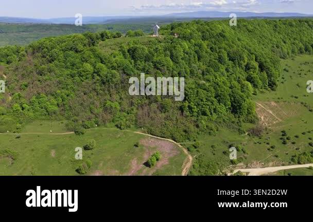 Aerial drone view of a forested hillside with a dirt road and a hilltop ...