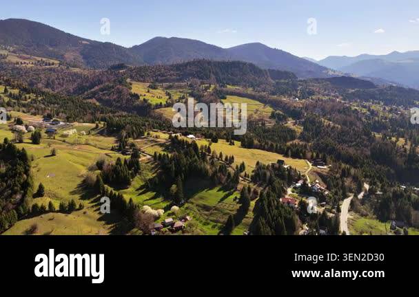 Aerial drone view of green hills, scattered houses, and forest patches ...