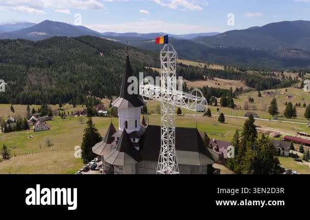 Aerial drone view of a Romanian flag waving above the large metal cross ...