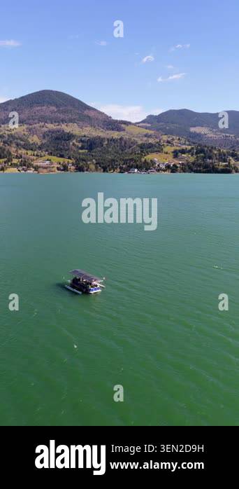 Aerial drone view of a small passenger boat moving across the Colibita ...