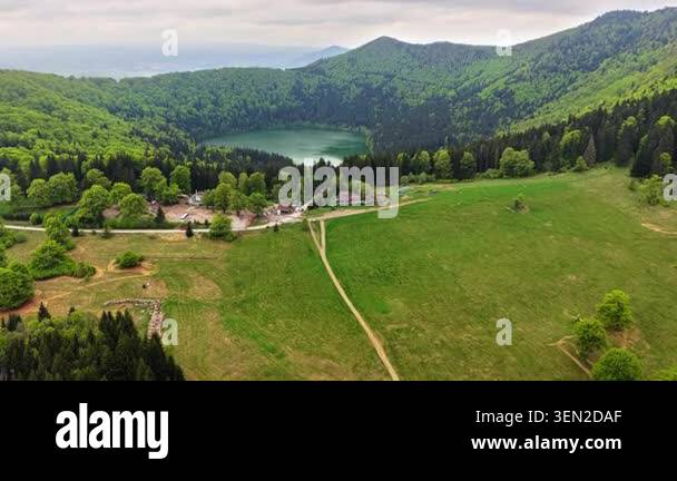 Aerial drone view of a round crater lake in a forested hollow, Lacul ...