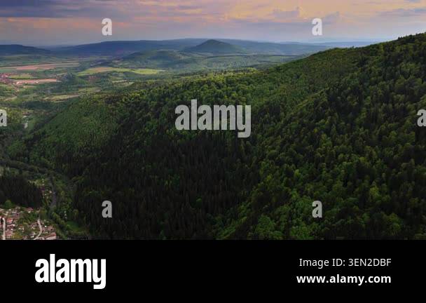 High-altitude aerial view from a forested edge over a lowland valley ...