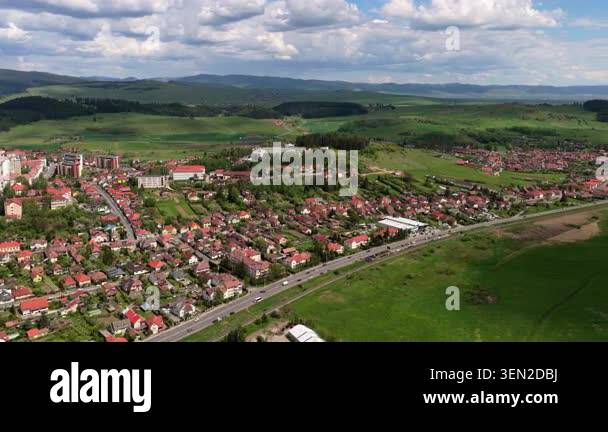 Aerial drone view of a town with red roofs and a highway below forested ...