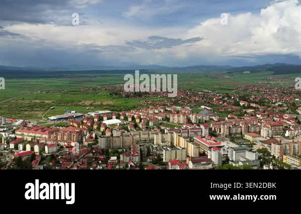High-altitude aerial view of a city with red roofs across a plain under ...