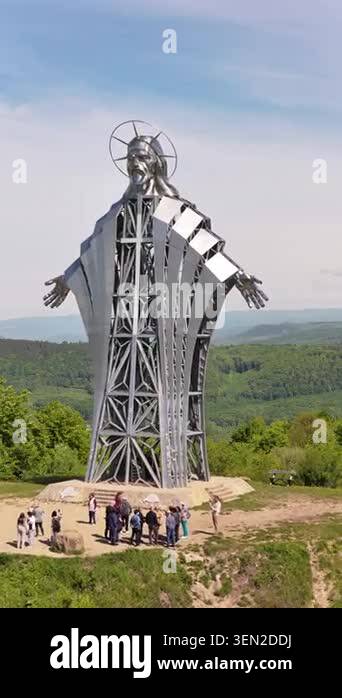 Aerial drone view of a steel Christ statue with visitors above a ...