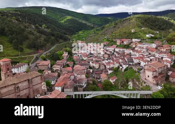 Aerial pull away reveal shot of an old mountain village with an arched ...