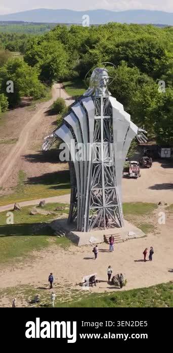 Aerial drone view of a steel Christ figure with visitors and a road ...