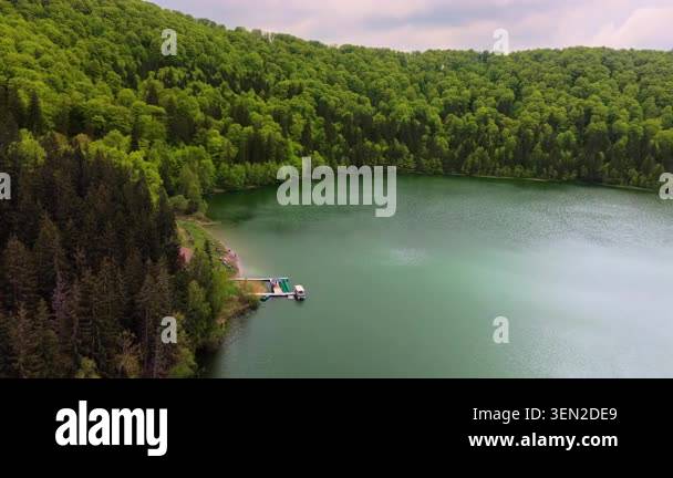 Overhead aerial view of a circular crater lake ringed by forest, Lacul ...