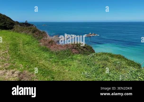 Aerial panoramic reveal shot of a wild rocky coastline and steep cliffs ...