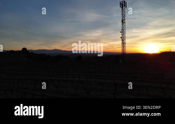 Aerial view of a telecommunication tower silhouette in a rural field at ...