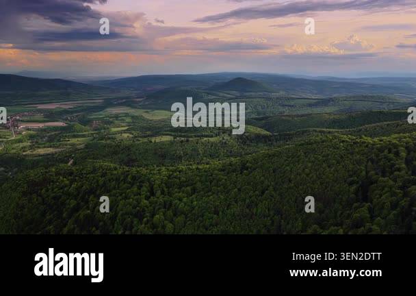 High-altitude aerial view of rolling forested hills and a wooded summit ...