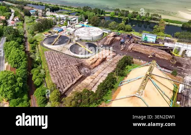 Industrial pulp and paper mill plant with log piles, wood chip storage ...