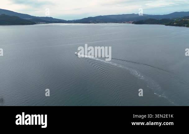 Aerial view of a white passenger boat sailing on the tranquil water of ...