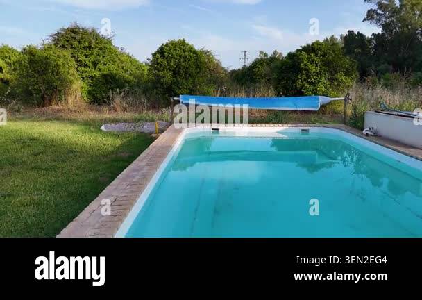 Uncovered swimming pool with turquoise water in a lush green backyard ...