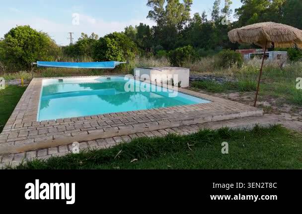 Ascending aerial view of a private swimming pool in a rustic backyard ...