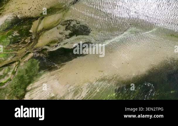 Calm aerial top down view of a river estuary. Clear water flows over ...