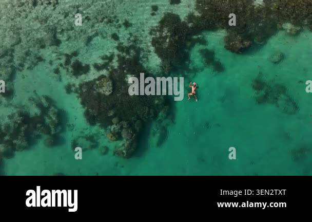 Turquoise lagoon beach, crystal clear shallow water with lone swimmer ...