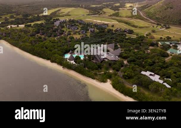 Aerial view of turquoise lagoon, resort roofs with pointed thatched ...