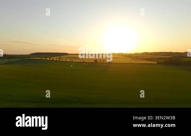 Sunset farmland aerial view across rolling crop fields in spring ...