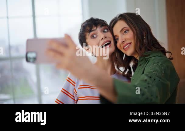Girlfriends taking picture smartphone standing light apartment together ...