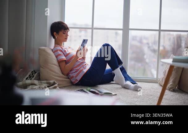 Home girl browsing cellphone reading message sitting comfortable floor ...