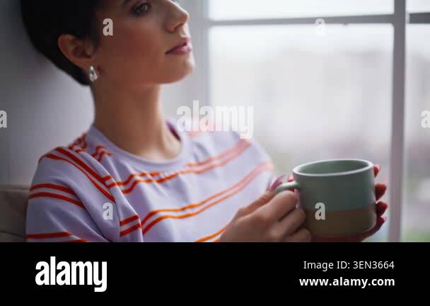 Closeup girl drinking coffee sitting living room floor looking ...