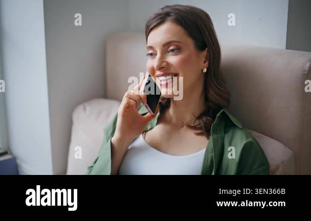 Joyful businesswoman talking cellphone sitting comfortable home ...