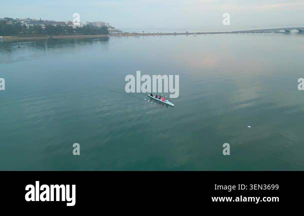 Sport Canoe with a team of four people rowing on tranquil water, Aerial ...