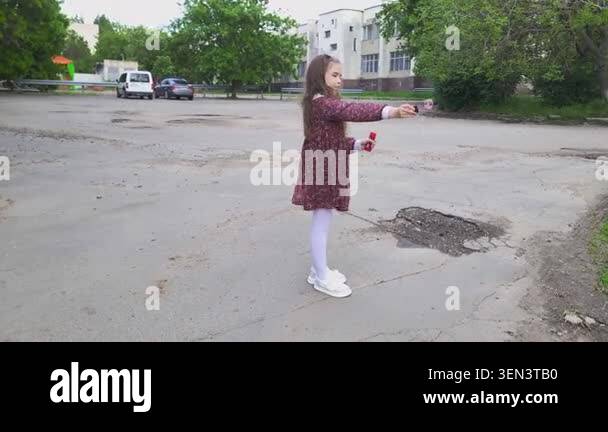 A cheerful little girl playing outdoors and blowing soap bubbles Stock ...