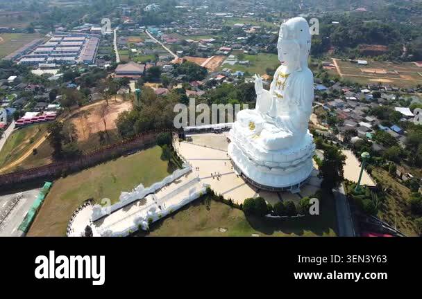 Majestic aerial view orbiting the giant white guan yin statue at wat ...