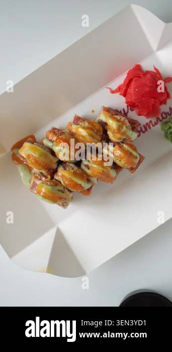 Womans hand using bamboo chopsticks to take a delicious baked sushi ...