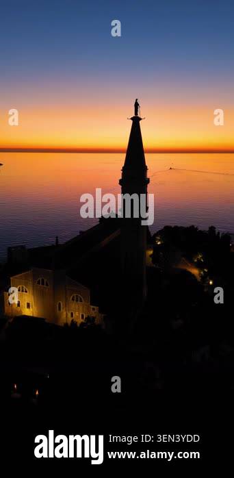 Saint euphemia church's bell tower silhouetted against a vibrant orange ...