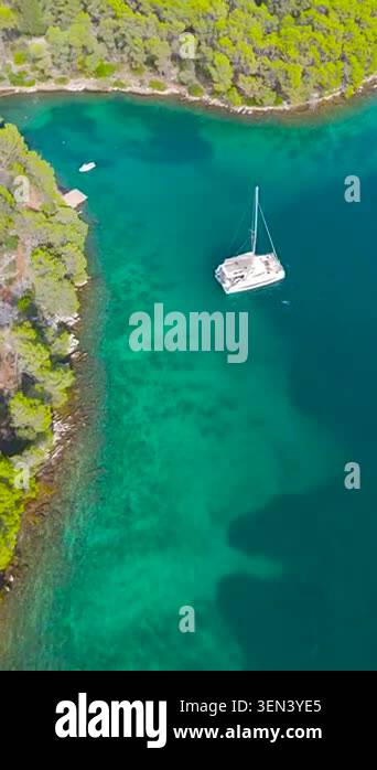 Idyllic aerial view of a white catamaran yacht anchored in a beautiful ...