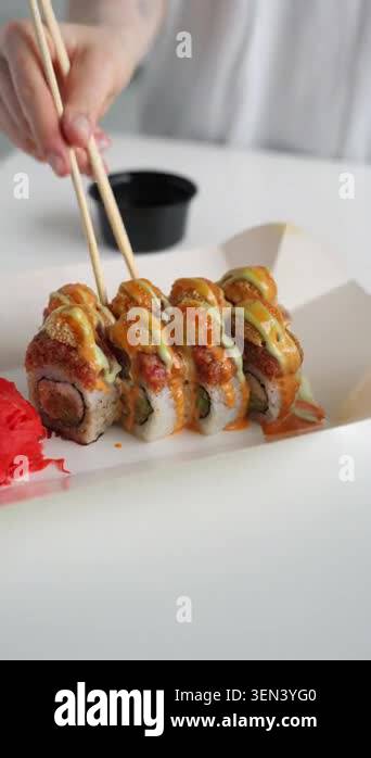 Close-up view of a person using wooden chopsticks to pick up a piece of ...