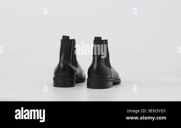 Classic black leather chelsea boots rotating in a studio. The elegant ...