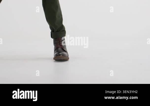 Cropped view of a mans legs in green rolled-up pants and brown leather ...