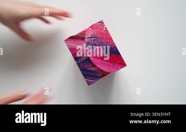 Feminine hands are unfolding a beautiful colorful paper box and opening ...