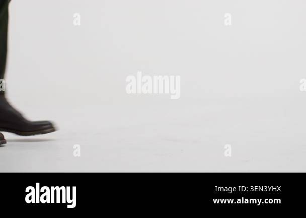 Lower body shot of a mans legs walking from left to right. He is ...