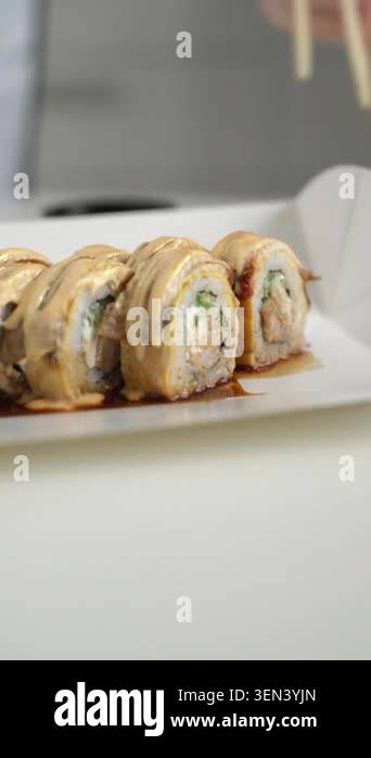 Close up of a person taking a fresh sushi roll with chopsticks and ...