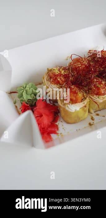 Close-up of a person taking a fresh sushi roll with chopsticks from a ...