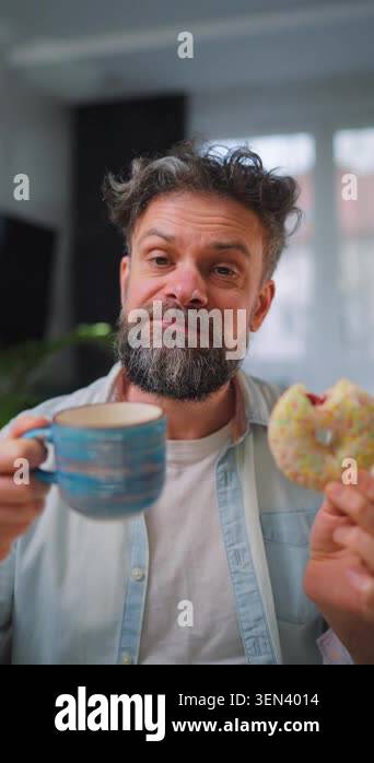 Sweet addiction concept. A man eats a donut and drinks coffee with ...