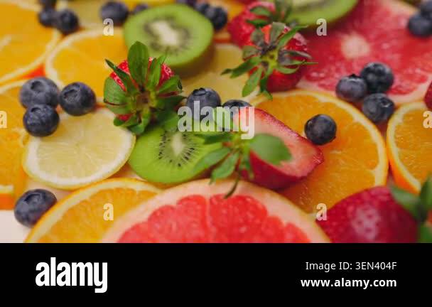 Background of fresh fruit slices with berries. Rotating shot of ...