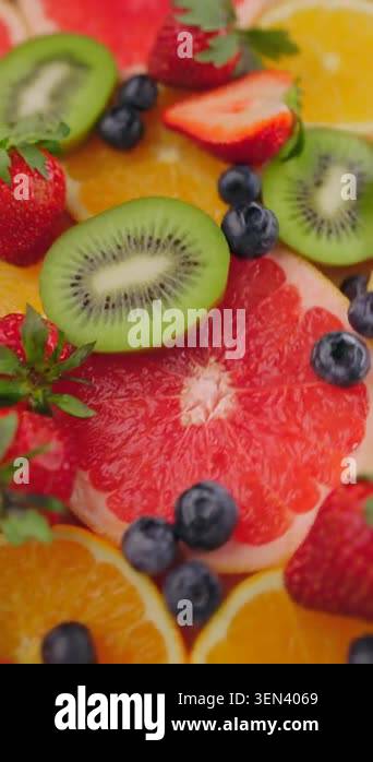 Background of fresh fruit slices with berries. Rotating shot of ...