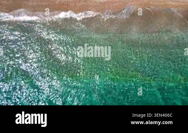 Top-down aerial drone view of pebble beach and crystal clear water ...