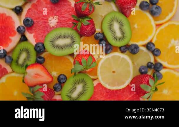 Background of fresh fruit slices with berries. Rotating shot of ...