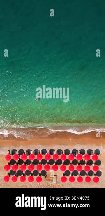 Top-down view of the idyllic golden sandy beach with red sun umbrellas ...