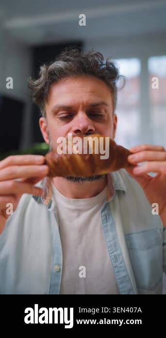 Happy caucasian man enjoying a fresh croissant and coffee for breakfast ...